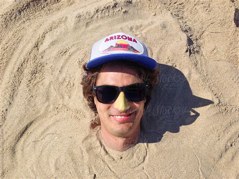 Man Wearing Sunglasses Buried In The Sand By Stocksy Contributor