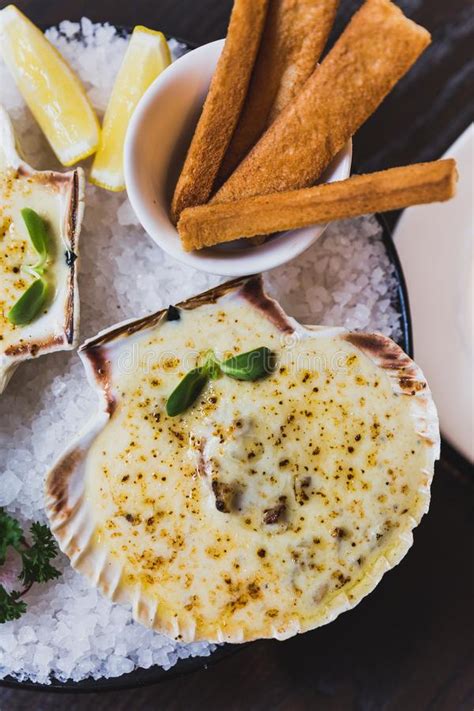 Top View Of Baked Scallops With Cheese Served With Sliced Lemon And