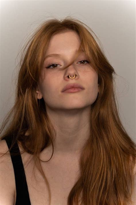 A Woman With Long Red Hair And Piercings On Her Nose Is Looking At The Camera