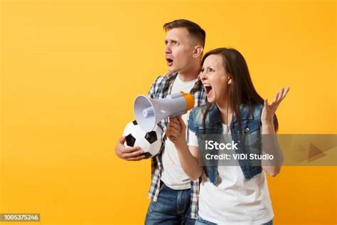 화가 생상 미친 커플 여자 남자 축구 팬 들 비명 손실의 화가 축구 공 노란 배경에 고립 된 확성기 좋아하는 팀의 목표 스포츠 가족 레저 라이프 스타일 개념입니다
