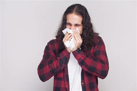 수염과 캐주얼 스타일에 검은 긴 곱슬 머리 감기 아픈 잘생긴 남자의 초상화는 조직과 재채기와 함께 서 있는 빨간 셔츠 체크 무늬 건강관리와 의술에 대한 스톡 사진 및 기타