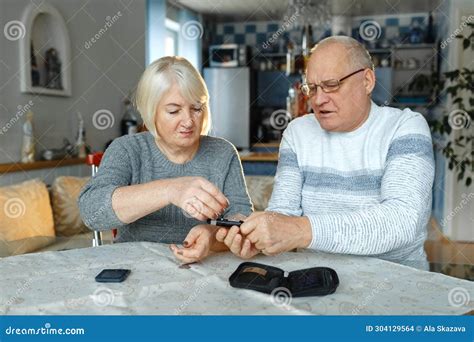An Elderly Woman Checks Her Blood Sugar Level Using A Glucometer While