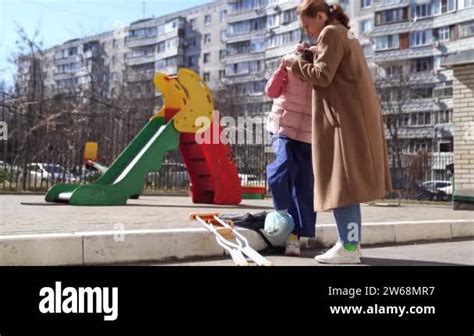 Mom Helps Her Daughter With A Broken Leg To Stand On Crutches In The