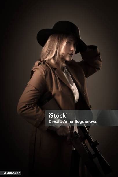 갈색 망토와 검은 모자를 쓰고 에어건을 손에 들고 있는 마피오소 여성 갱스터 스타일 사진 촬영 갈색에 대한 스톡 사진 및 기타 이미지 Istock