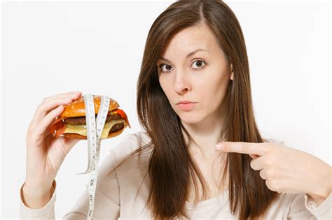 여자를 가까이 손 주위에 테이프를 측정 하는 재단사와 함께 햄버거 흰색 배경에 고립에서 보유 합니다 적절 한 영양 섭취 또는 고전적인 미국의 패스트 푸드입니다 광고에 대 한