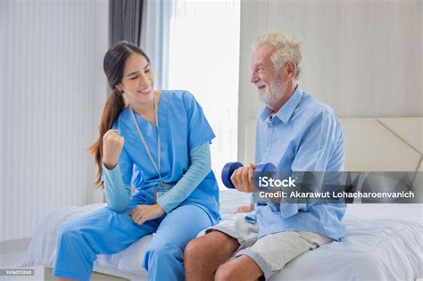 호스피스 간호사는 침대에있는 백인 남성이 가정 간호 재활 및 치료 후 회복 과정을 위해 연금 퇴직 센터에서 근력을 행사할 수 있도록 돕고 있습니다 재활 센터에 대한 스톡