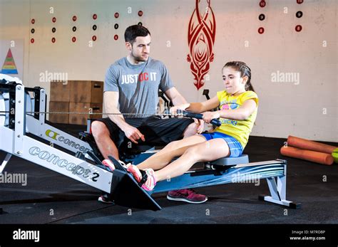 A Young Girl Been Given A Lesson On A Rowing Machine In A Gym Stock