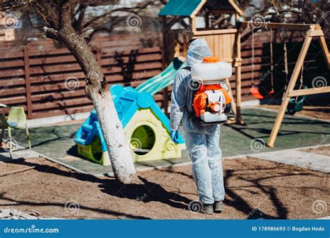 Man Wearing Protective Hazmat Sterile Suit Spraying Disinfectant And