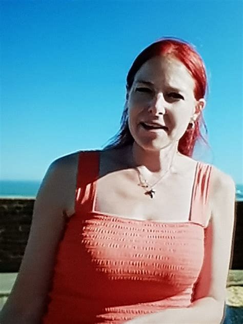 A Woman With Red Hair Is Standing Near The Ocean