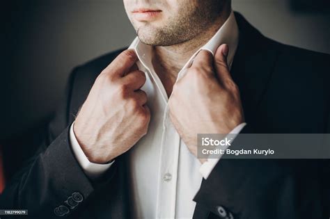 흰색 셔츠의 칼라를 들고 검은 정장에 세련된 신랑 방에 창 근처에 포즈 자신감있는 남자는 결혼식을 준비 아침에 준비 정장 사업가
