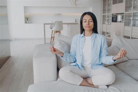 Premium Photo Female Practicing Yoga Sitting In Lotus Pose On Sofa At