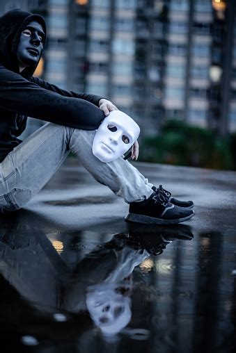 버려진된 건물의 옥상에서 비에 앉아 흰 마스크를 들고 검은 마스크와 미스 테리 까마귀 남자의 반사 양극성 장애 또는 주요 우울증 장애입니다 우울증 개념 가린 얼굴에 대한