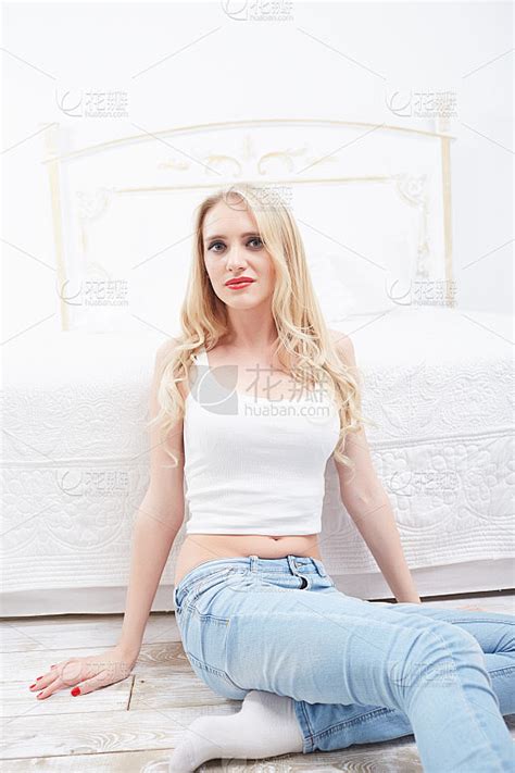 漂亮的金发美女坐在床边的地板上
