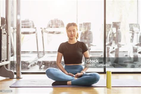 명상 운동에 앉아 요가를 연습하는 젊은 아시아 여성 운동복을 입고 운동하는 차분한 자세 명상 세션 실내 스포츠 클럽 인테리어