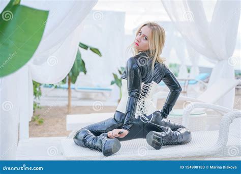 Slim Young Blonde Slavery Girl In Black Latex Catsuit With White Corset