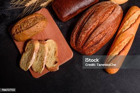 어두운 배경에 곡물과 밀 콘을 곁들인 신선한 향기로운 빵 나무 테이블 배경에 구운 빵의 구색 갈색에 대한 스톡 사진 및 기타