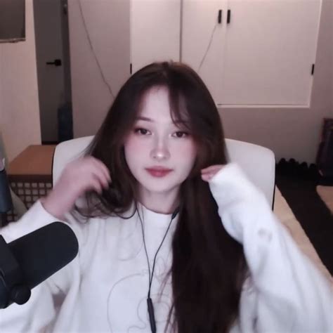 A Woman With Long Hair Sitting In A Chair And Holding Her Hand Up To