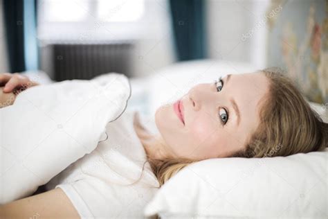 Mujer Rubia Joven Acostada En Su Cama Debajo De La Manta Y Mirando