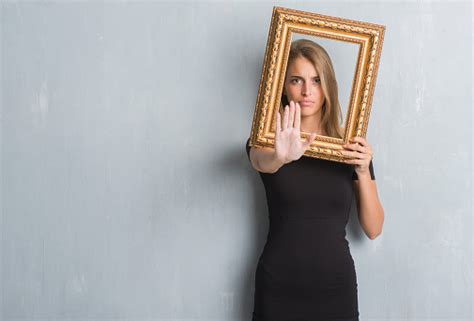 그런 지 위에 아름 다운 젊은 여 자가 심각 하 고 자신감 표현 방어 제스처 정지 표시를 하 고 오픈 손으로 빈티지 프레임을