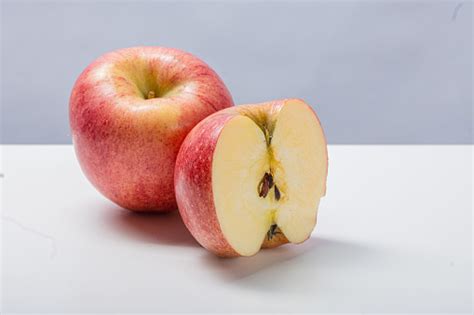 깨끗한 흰색 표면과 밝은 배경에 씨앗이 있는 전체 빨간 사과와 반 컷 사과는 육즙이 많은 질감 신선한 과육 및 잘 익은 건강한 과일의 자연스러운 색상을 보여줍니다 겉껍질에