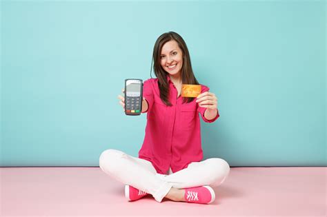 전체 길이 장미 셔츠에서 여자의 초상화 바닥에 앉아 흰 바지 잡고 밝은 핑크 블루 파스텔 벽 배경 스튜디오에 고립 된 터미널 카드 패션 라이프 스타일 개념입니다 복사 공간을