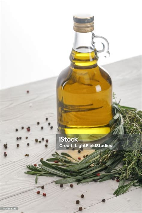 로즈마리와 백리향 덩어리 근처의 오일 병 흰색 나무 표면에 흩어져있는 빨간색과 검은 후추 0명에 대한 스톡 사진 및 기타 이미지