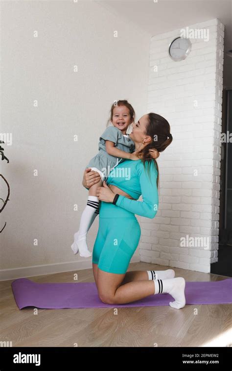 A Young And Athletic Mom In A Tracksuit Hugs Her Daughter After A Joint
