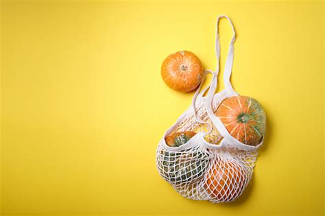 신선한 호박 쇼핑 환경 친화적 인 메쉬 백의 패티칸 스쿼시 노란색 배경에 단풍 개념 유기농 야채 수확 상단 보기 플랫 레이