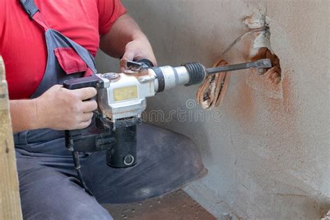 Perforador De La Tenencia Del Hombre En Manos Y Pared De Perforación