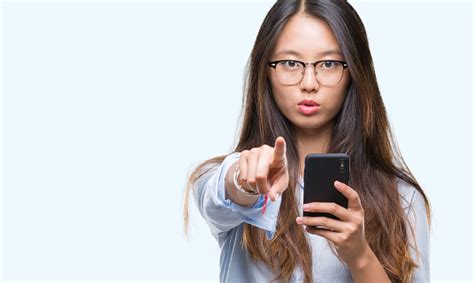 스마트폰 사용 하는 젊은 아시아 여자 문자 메시지 격리 카메라 하 고 당신에 게 손가락으로 가리키는 배경 손 기호 정면에서