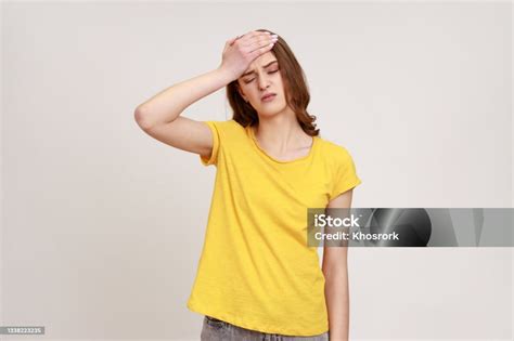노란 티셔츠를 입은 어린 나이의 아름다운 여성의 초상화가 얼굴 손바닥 제스처로 서 서 자신을 비난하고 나쁜 기억 때문에 후회를