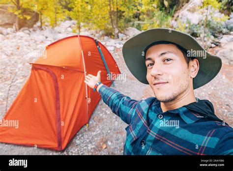 Happy Man Traveler Naturalist Against The Backdrop Of A Camping Tent