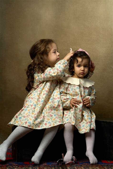 Two Sisters Sitting On Blocks Cute Sisters In Matching Floral Dresses