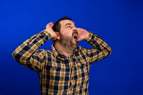 캐주얼 한 격자 무늬 셔츠를 입은 젊은 잘 생긴 남자는 고립 된 파란색 배경 미친 위에 서 있고 머리에 손으로 무서워하고 입을 벌리고 충격을 두려워하고 놀랐습니다 겨울에