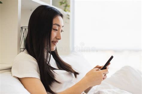 Young Asian Woman Using Smartphone On Bed For Online Activities Stock