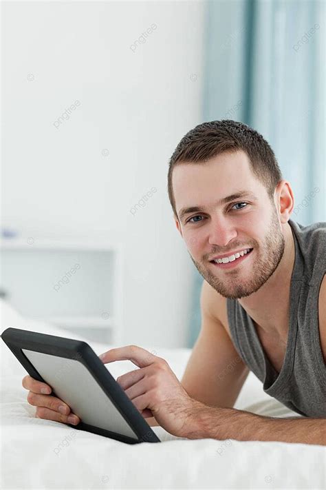 Handsome Man Enjoying His Tablet While Lying Down Photo Background And Picture For Free Download
