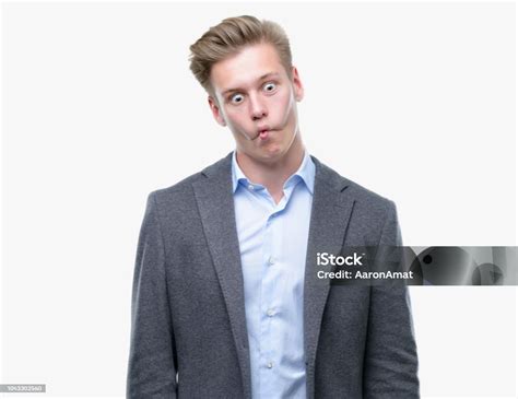 젊은 잘생긴 금발 비즈니스 남자 만드는 물고기 얼굴 입술 고 우 스 꽝 스러운 제스처 재미 있는 식입니다 검은색에 대한 스톡