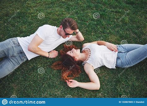 A Romantic Couple Of Young People Lying On The Grass In The Park Top