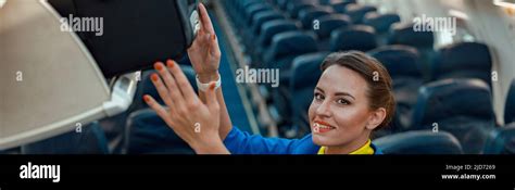 Stewardess Putting Travel Bag In Overhead Luggage Shelf In Airplane