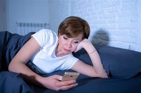 늦은 밤에 어두운 침실에 침대에 누워 스마트 휴대 전화를 사용 하 여 깨어 있는 젊은 매력적인 여자 채팅 및 인터넷 중독 모바일 학대와 불면증 개념에 메시지를 보내는