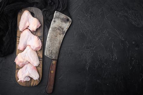 검은 돌 배경에 오래된 정육점 칼 칼을 가진 신선한 생 닭 날개 상단 보기 플랫 레이 텍스트 복사 공간 고기 칼에 대한 스톡