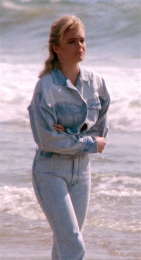 A Woman Standing On Top Of A Sandy Beach Next To The Ocean With Her