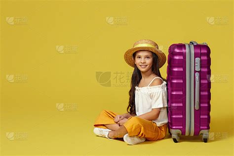 小女孩拿着旅行箱和护照坐在地板上