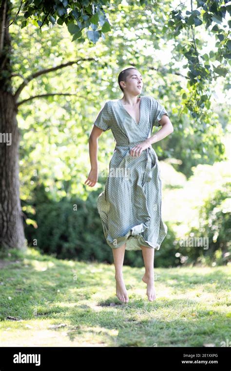 Non Binary Shaved Head Biological Female In Green Dress Jumping On