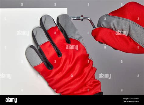 Furniture Assembler In Red Gloves Is Screwing In A Screw With A Hex