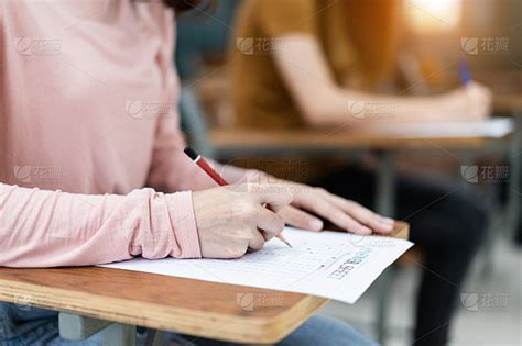 近距离的年轻女大学生集中做考试在教室里。女同学在教室里把考试答案写在答题纸上。