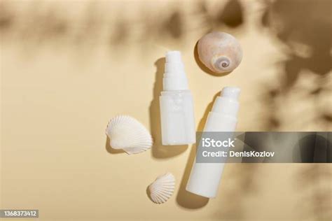 단단한 그림자가 있는 베이지 색 배경에 조개가 있는 흰색 화장품 병과 항아리 세트 미녀 살롱과 무두질여름 화장품의 컨셉 메이크업