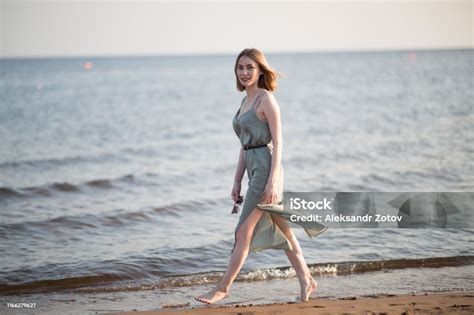 일몰에 바다 해안에서 걷는 녹색 여름 드레스를 입고 짧은 밝은 머리를 가진 젊은 아름다운 슬림 여성 가냘픈에 대한 스톡 사진 및 기타 이미지 Istock