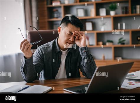 Sad Tired Adult Chinese Man Takes Off His Glasses Rubs Eyes And Rests