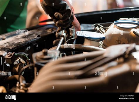 Mechanic Using Socket Wrench Underneath Car Hood For Engine Repair
